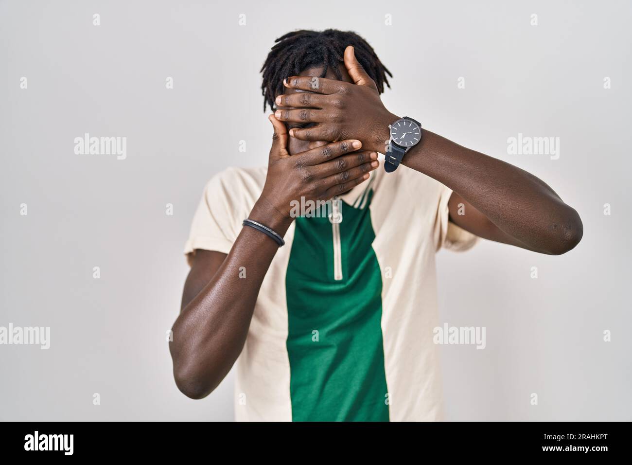 African man with dreadlocks standing over isolated background covering ...