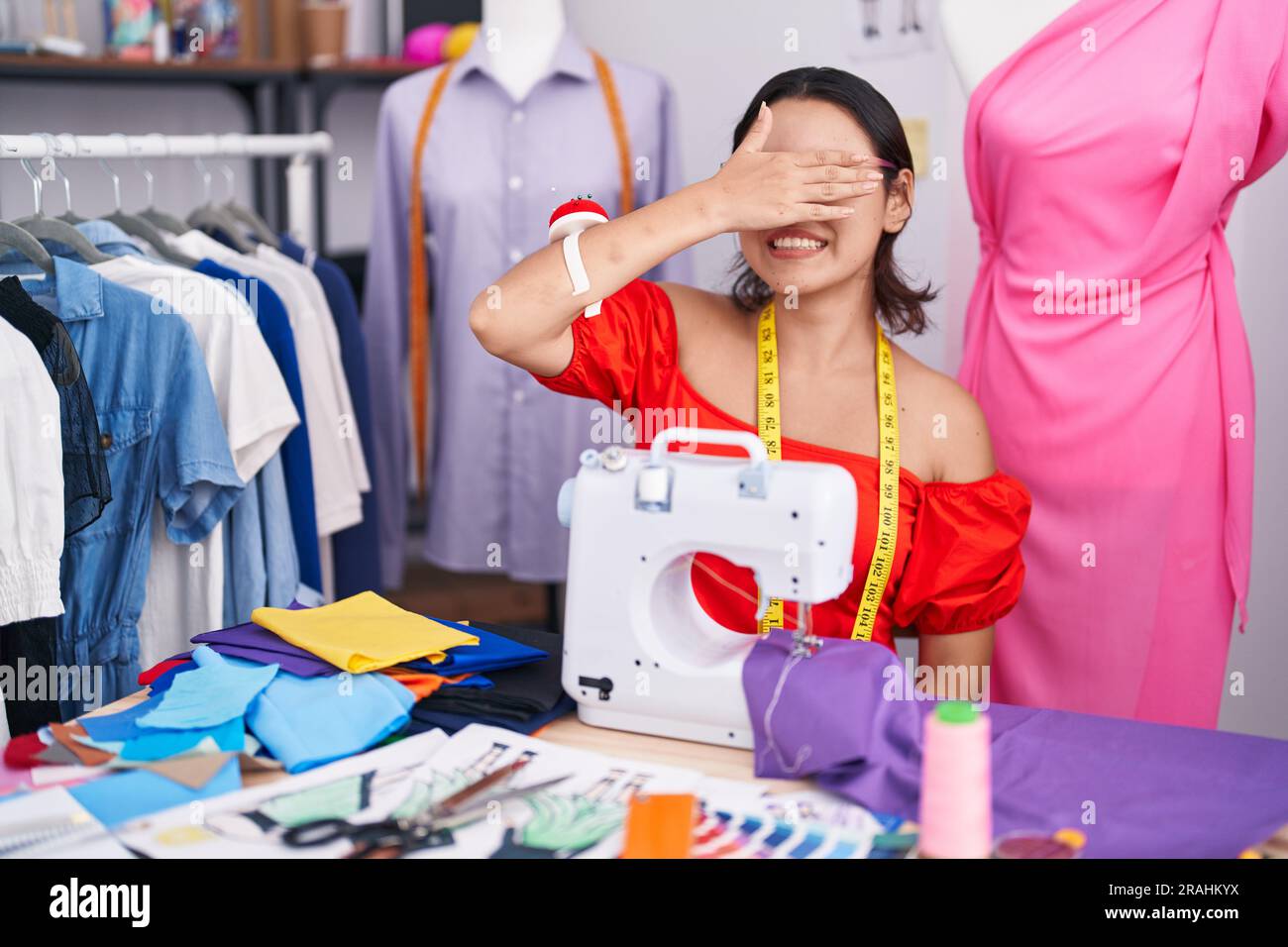 Hispanic young woman dressmaker designer using sewing machine smiling ...