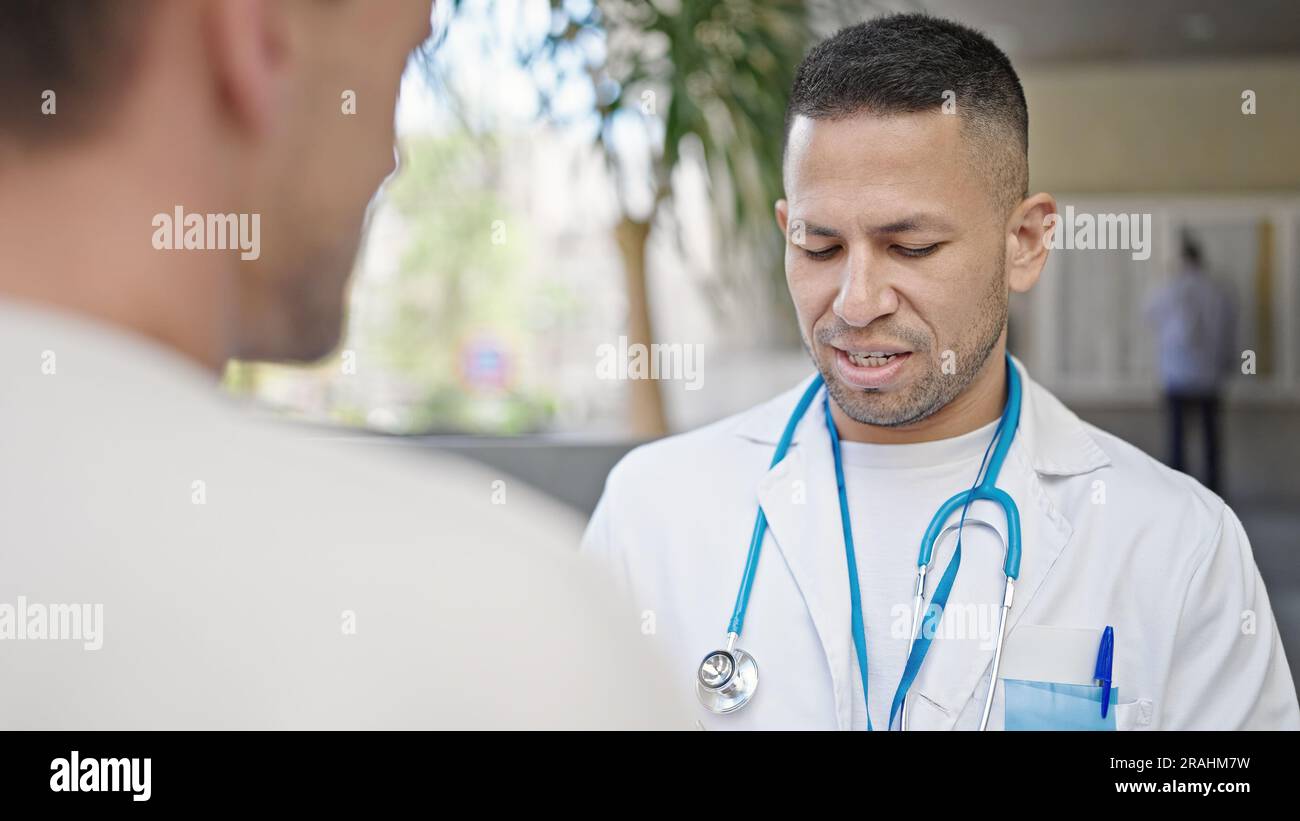 Two men doctor and patient having medical consultation speaking at ...