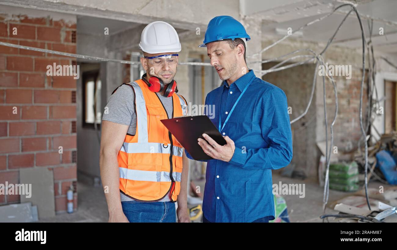 Two men builder and architect writing document speaking at construction ...