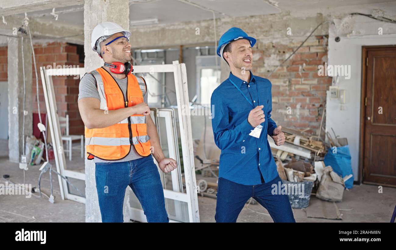 Two men builder and architect smiling confident dancing at construction ...