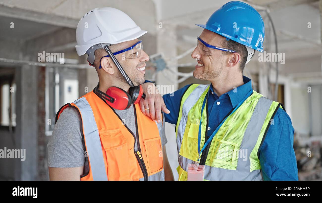 Two men builders smiling confident standing together at construction ...