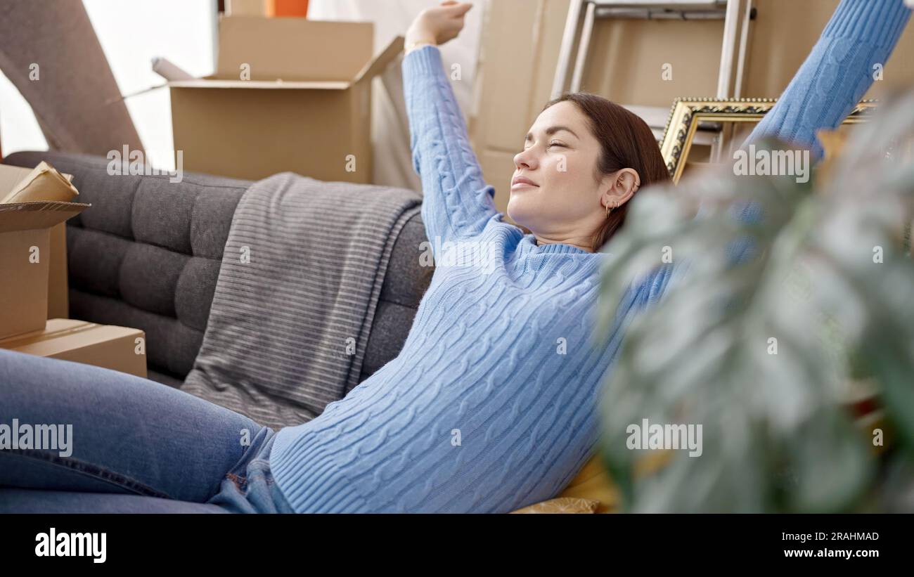 Young caucasian woman resting sitting on the sofa stretching arms at ...