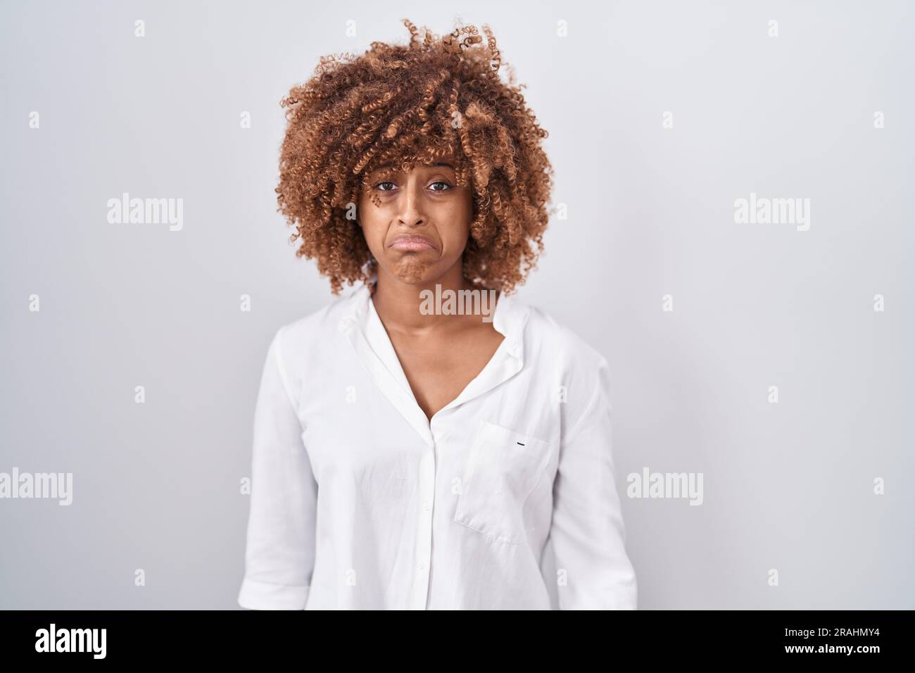 Young hispanic woman with curly hair standing over white background ...