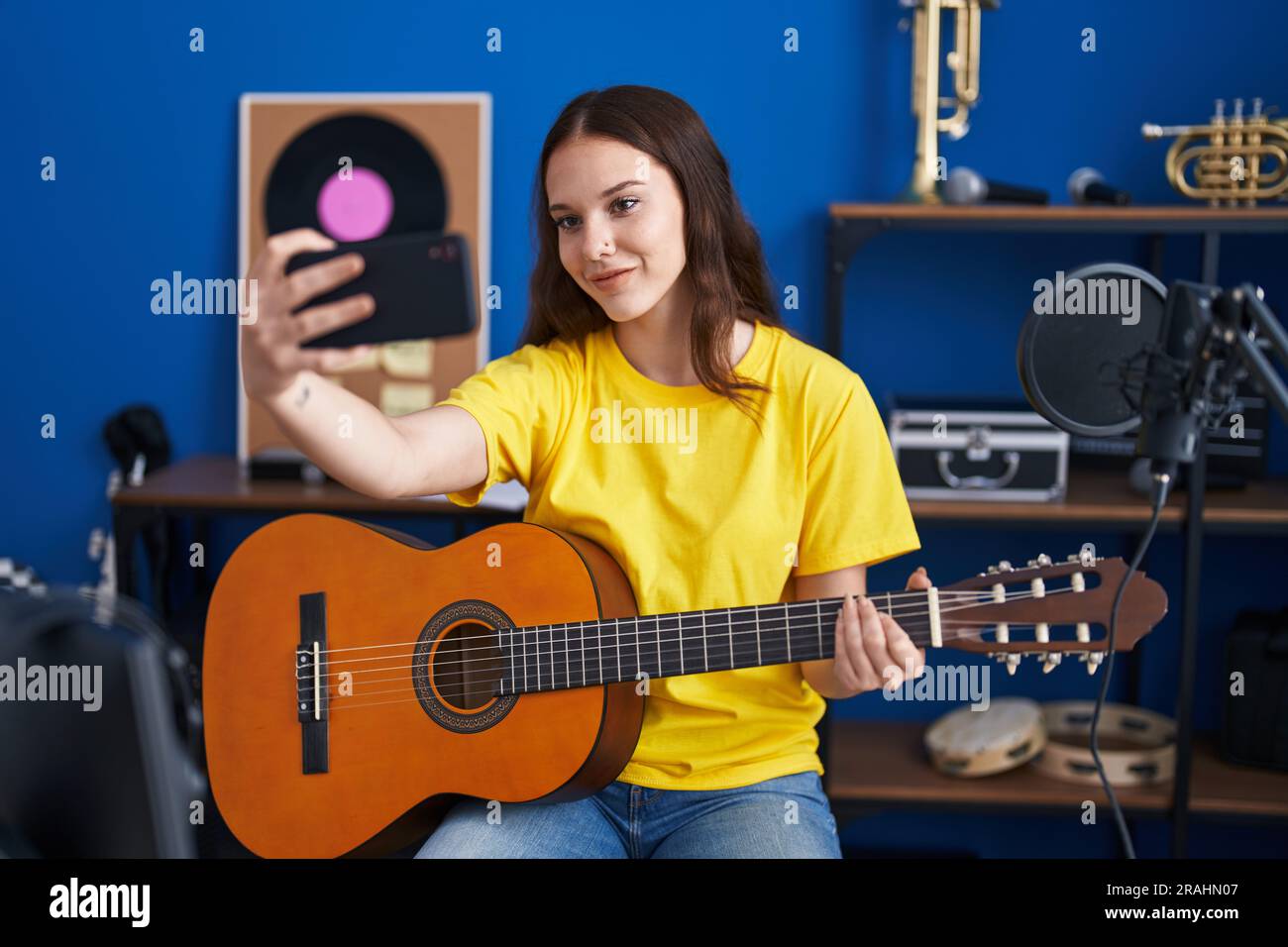 Young woman musician make selfie by smartphone holding classical guitar ...