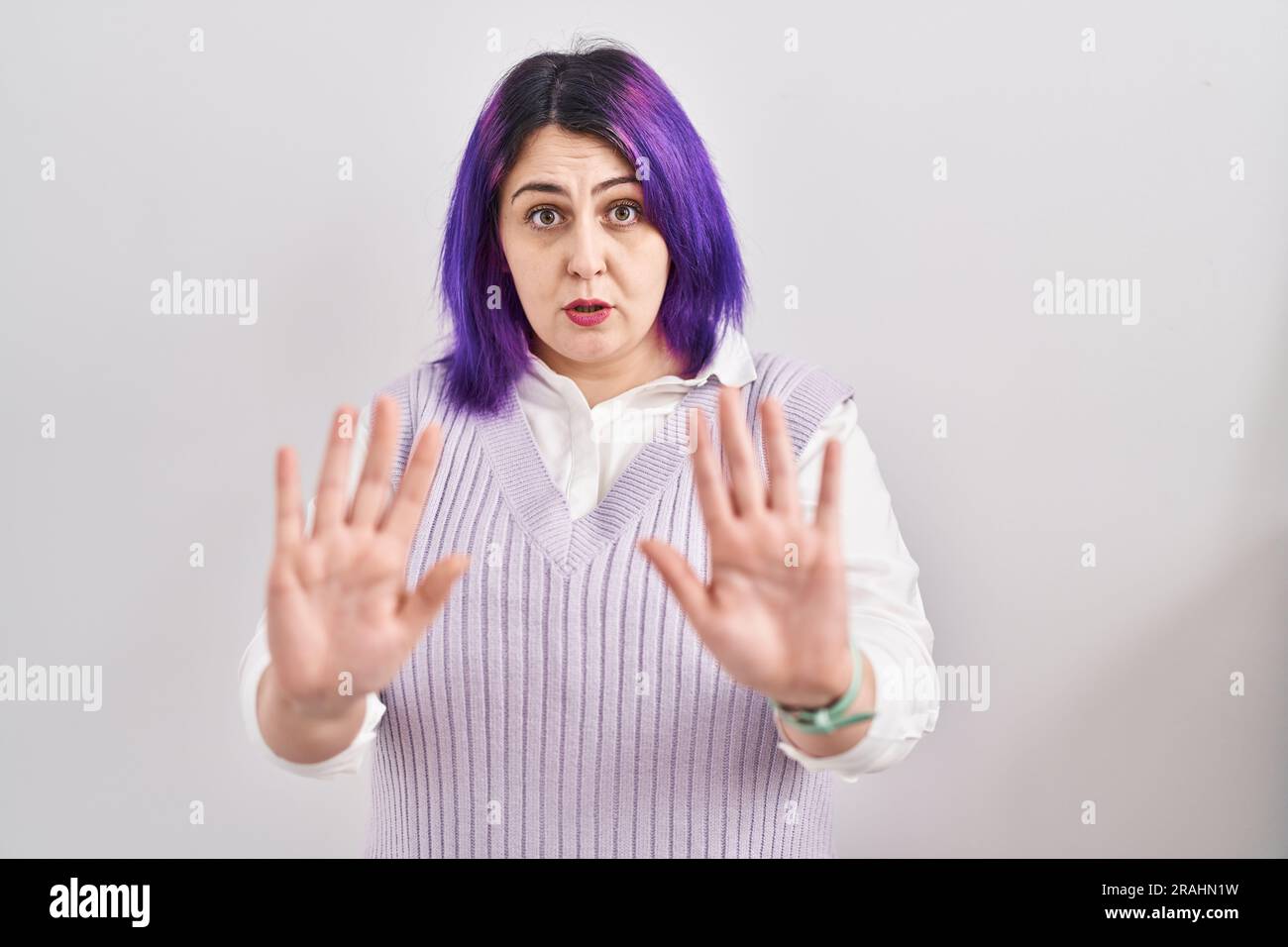 Plus size woman wit purple hair standing over white background moving ...