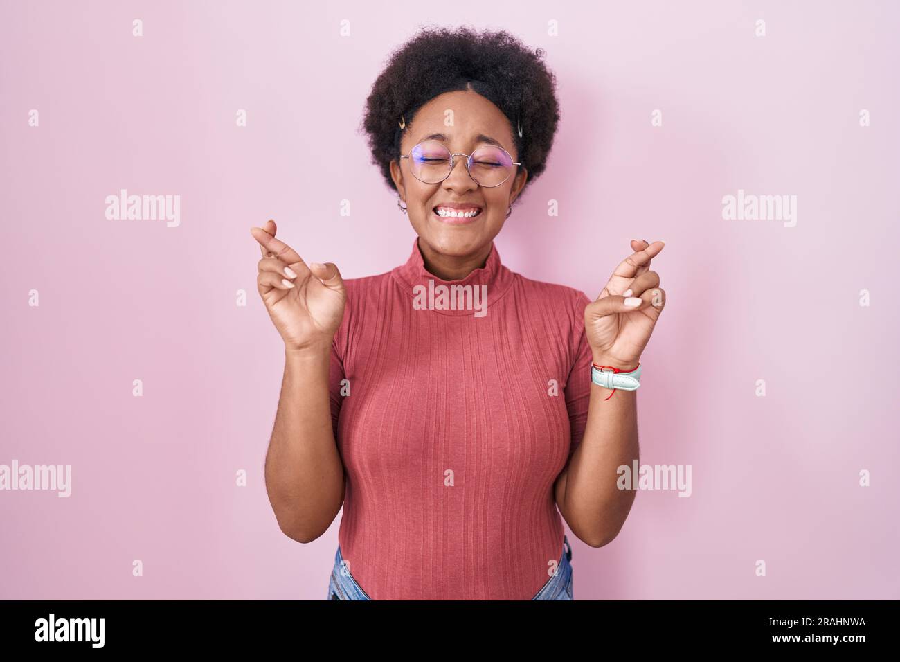 Beautiful african woman with curly hair standing over pink background ...