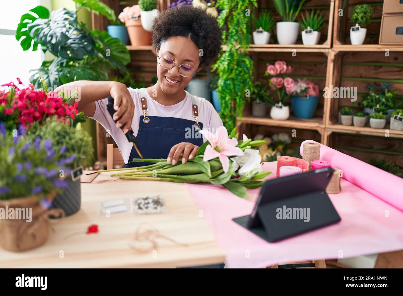 African american woman florist make bouquet of flowers watching video ...