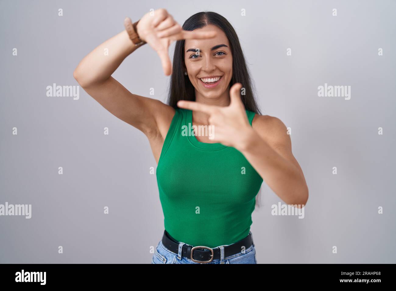 Young woman standing over isolated background smiling making frame with ...