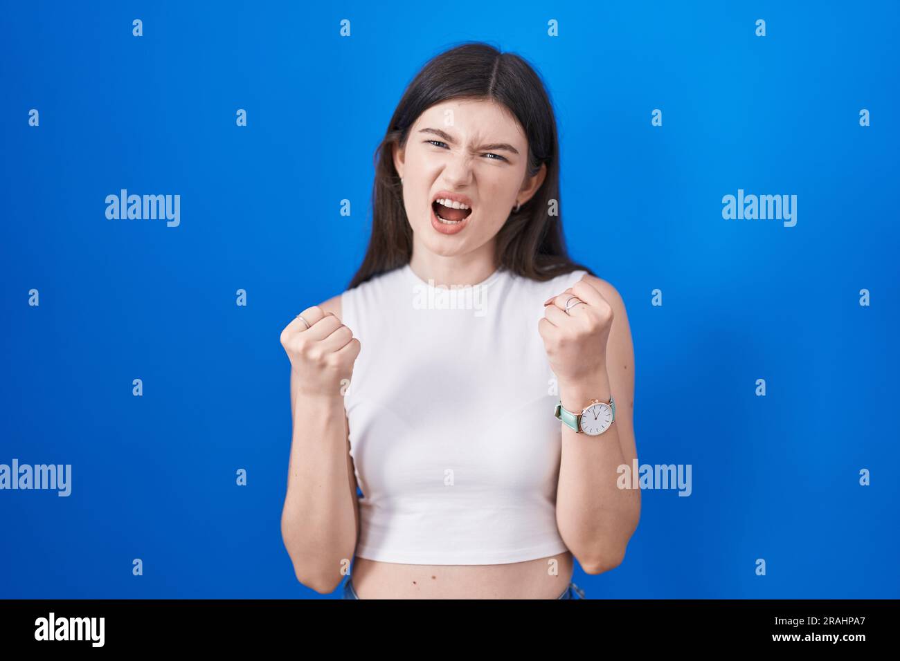 Young caucasian woman standing over blue background angry and mad ...