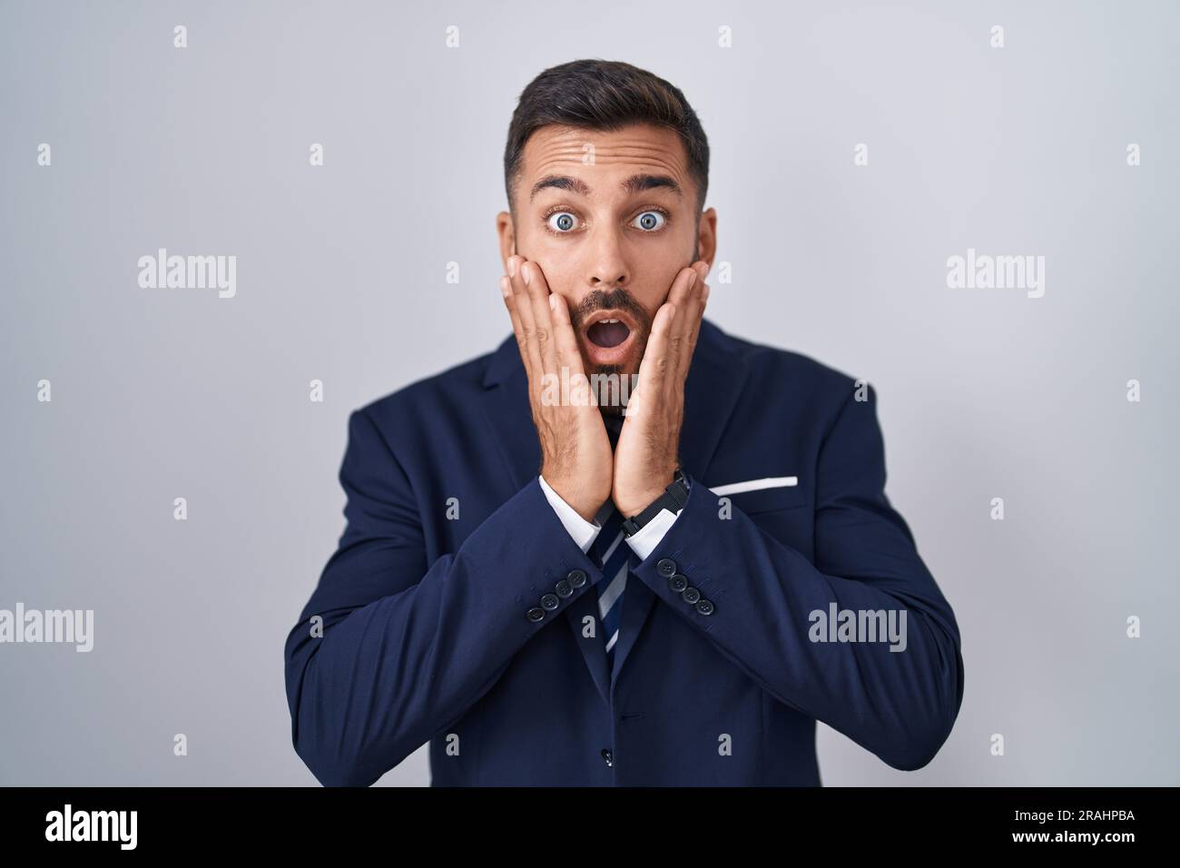 Handsome hispanic man wearing suit and tie afraid and shocked, surprise ...