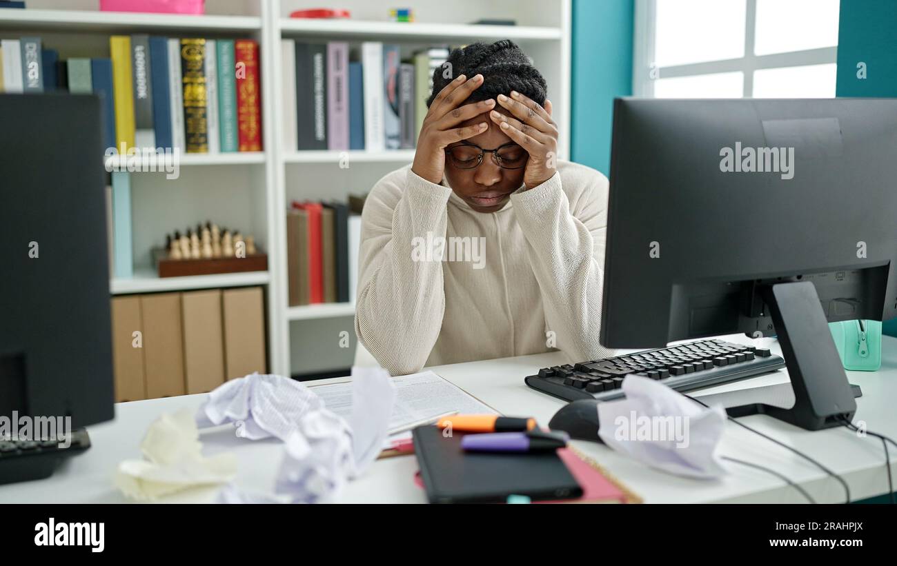 African american woman student using computer stressed at library ...