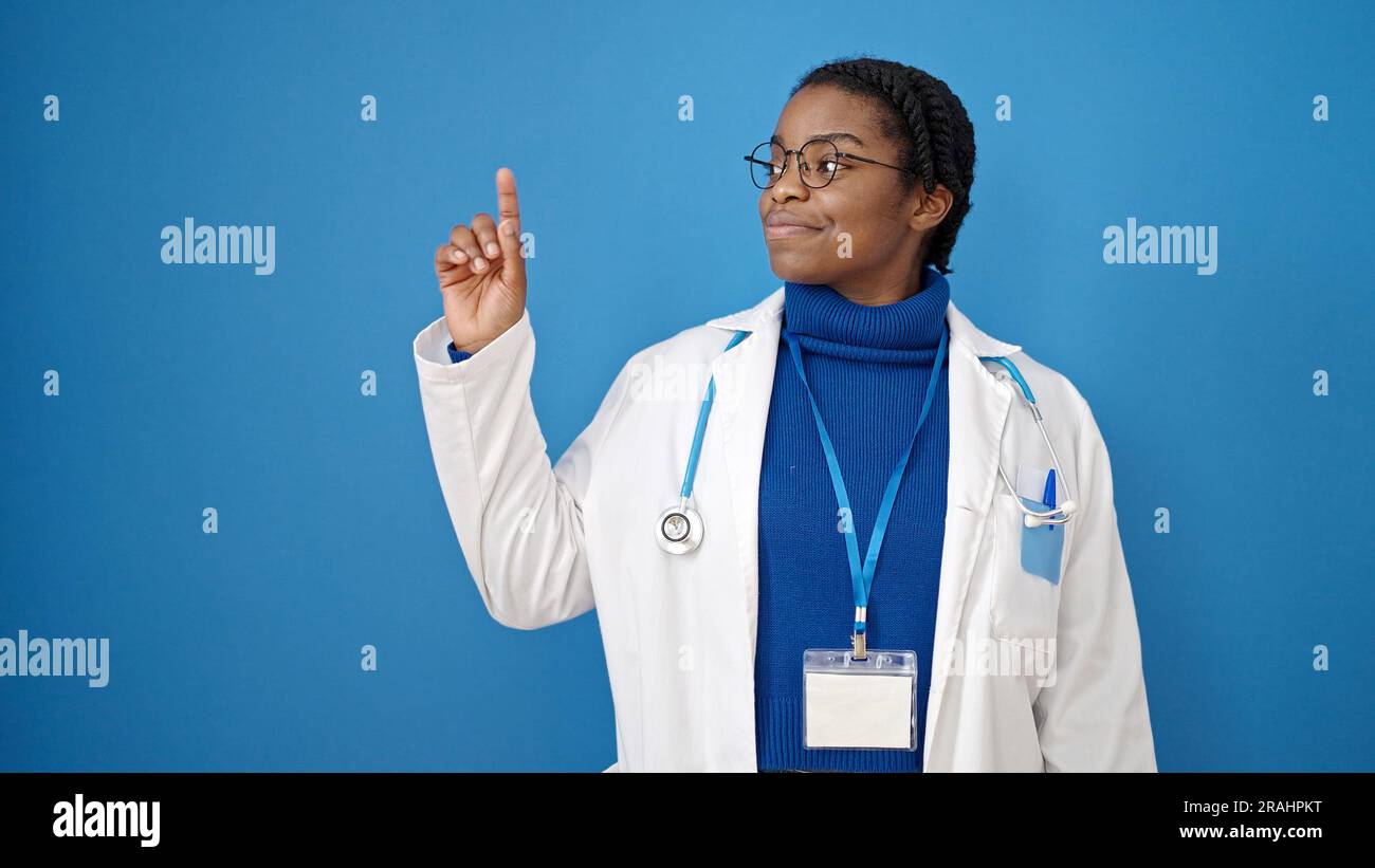 African american woman doctor smiling pointing to the side over ...