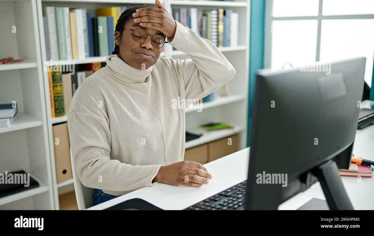 African american woman student using computer stressed at library ...