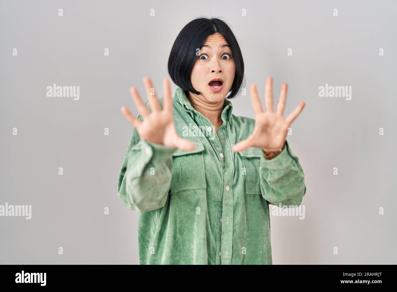Young asian woman standing over white background afraid and terrified ...