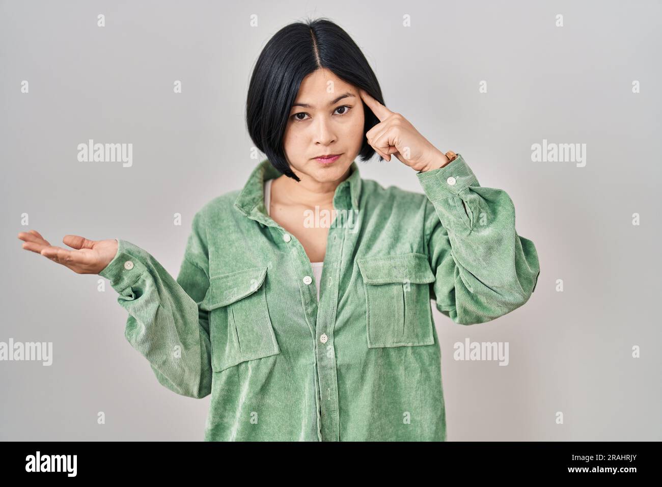 Young asian woman standing over white background confused and annoyed ...