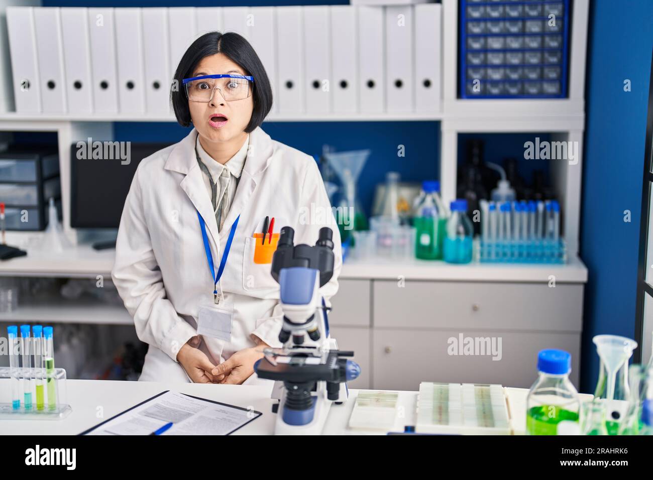 Young asian woman working at scientist laboratory scared and amazed ...