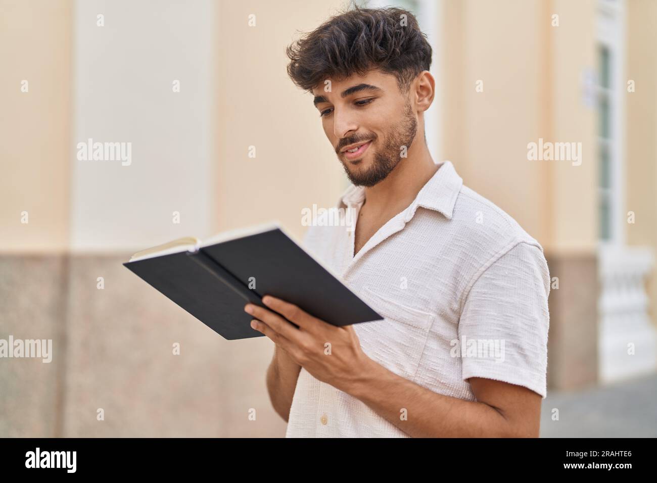 Young arab man smiling confident reading book at street Stock Photo - Alamy