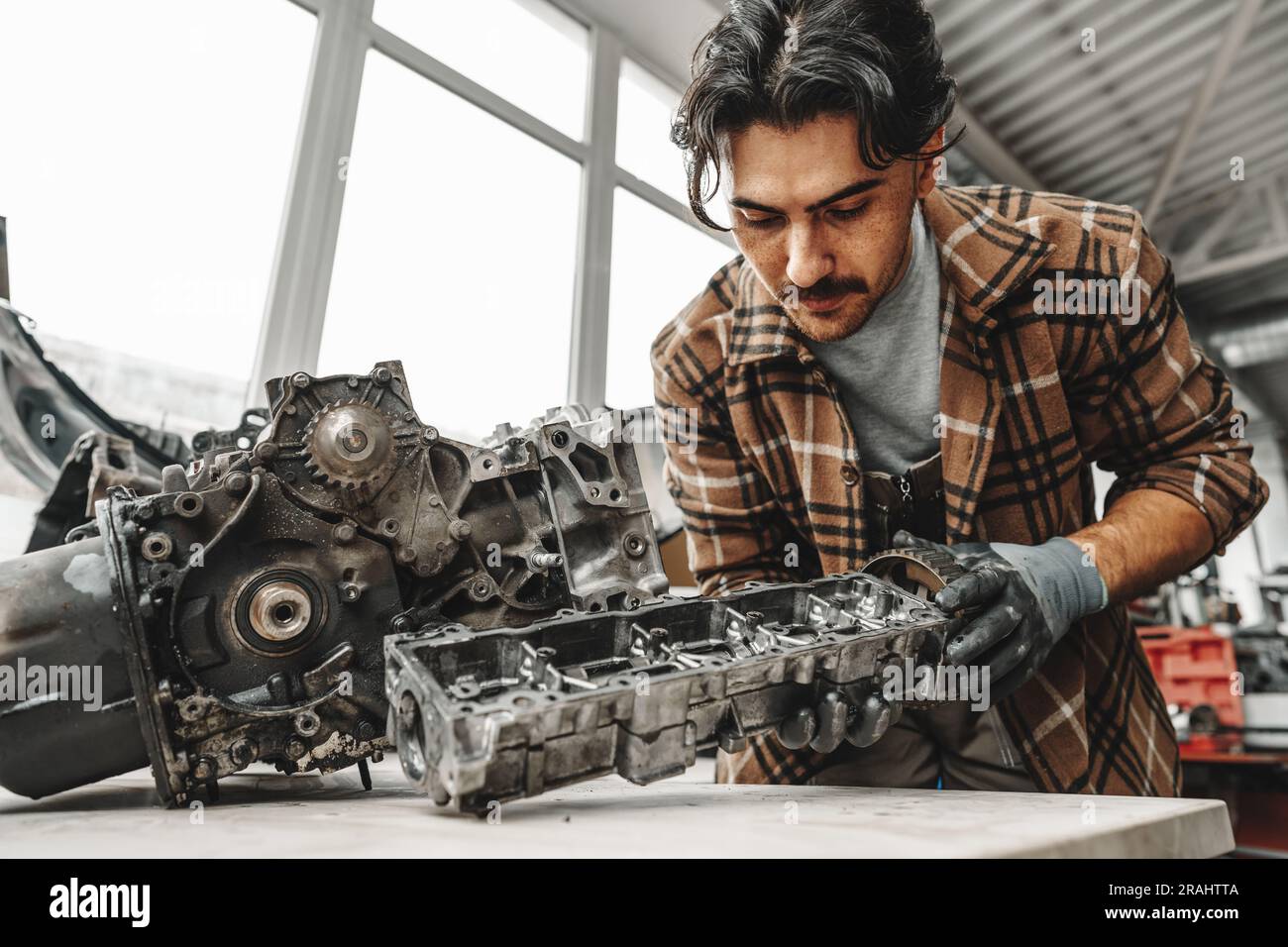 Workman disassembling car engine at the working table of the car ...