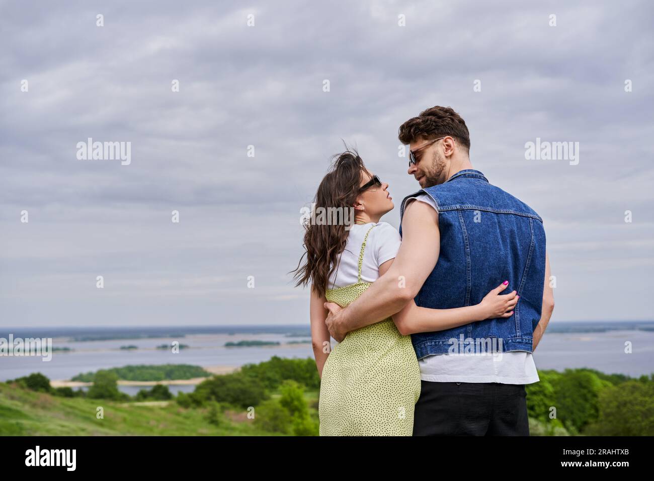 Side view of trendy romantic couple in sunglasses and summer outfits ...