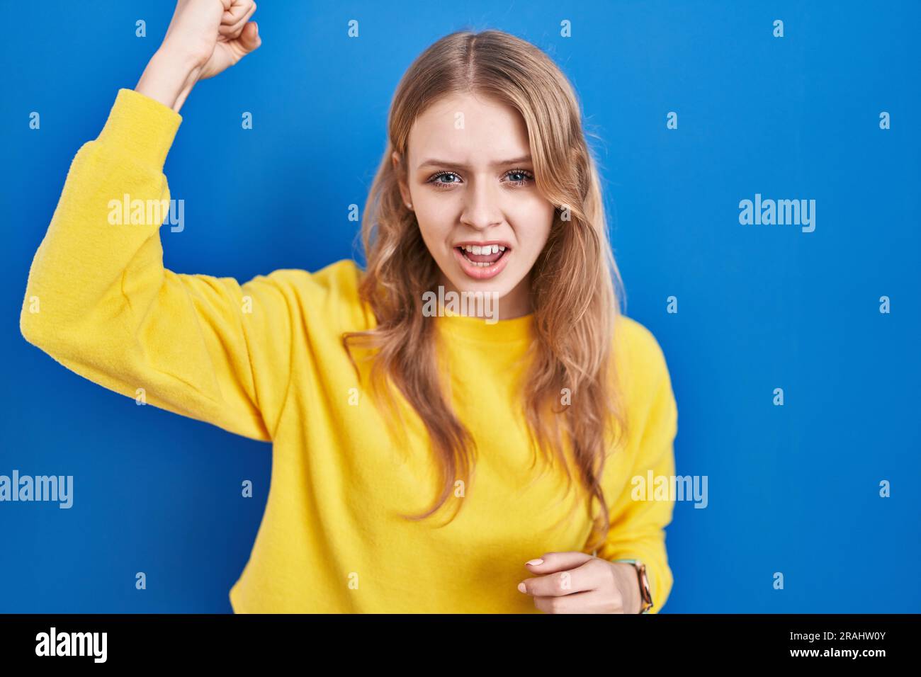 Young caucasian woman standing over blue background angry and mad ...