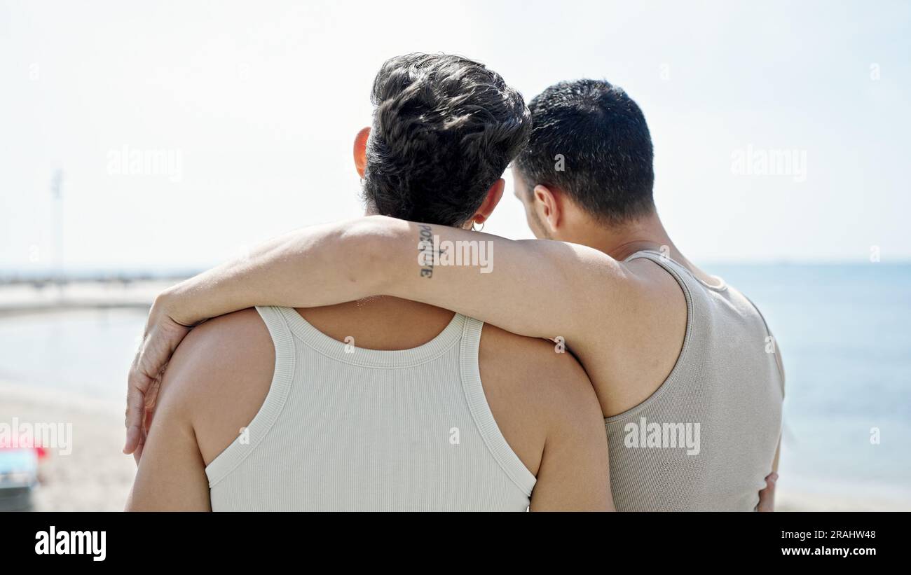 Two men couple hugging each other backwards at seaside Stock Photo - Alamy