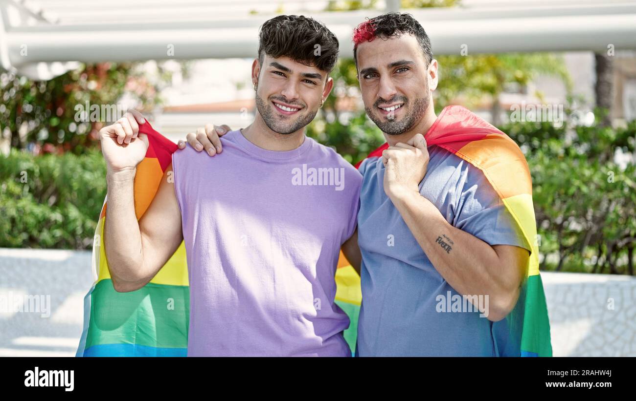 Two men couple hugging each other holding homosexual flag at park Stock ...