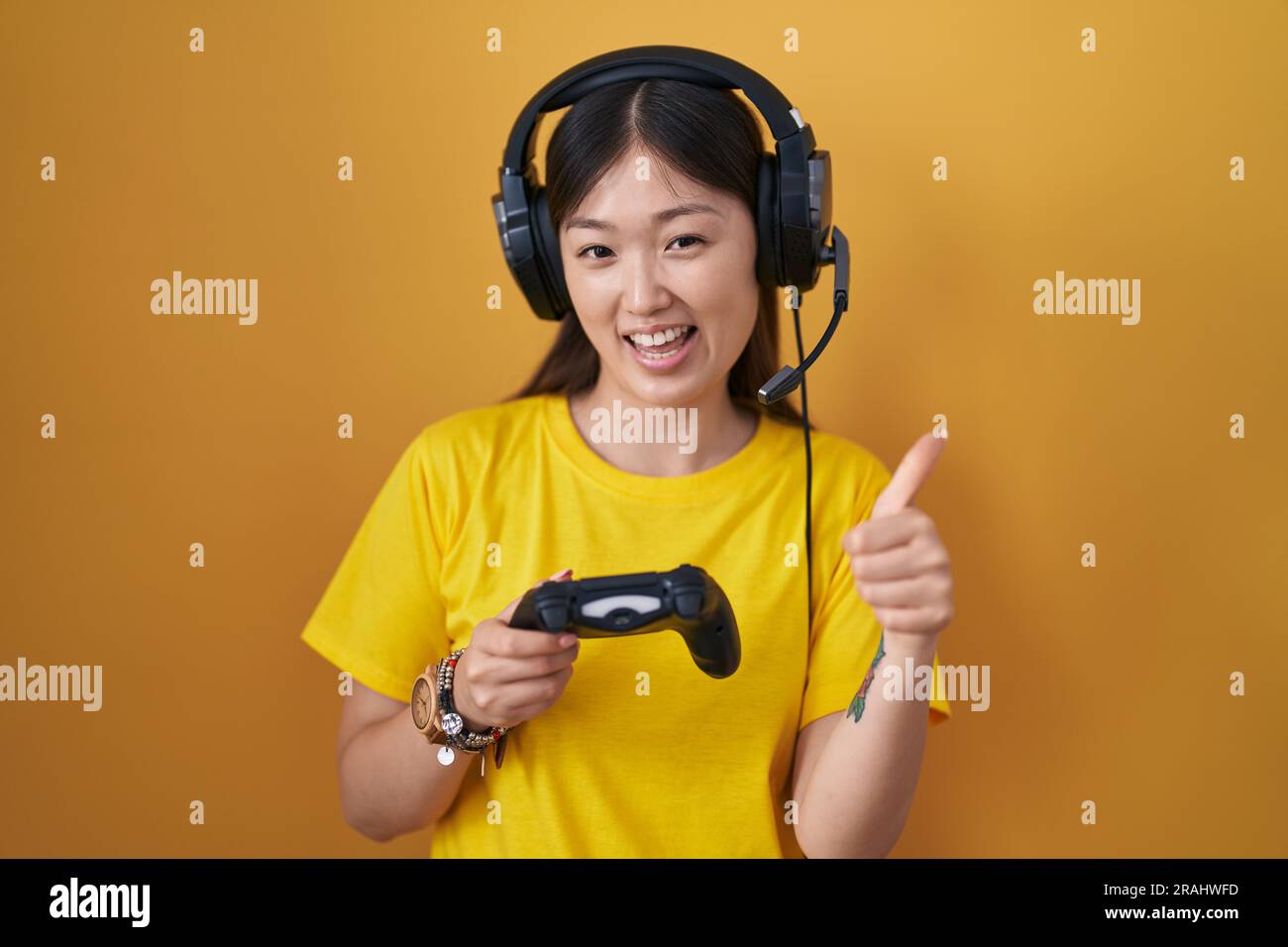 Chinese young woman playing video game holding controller approving ...