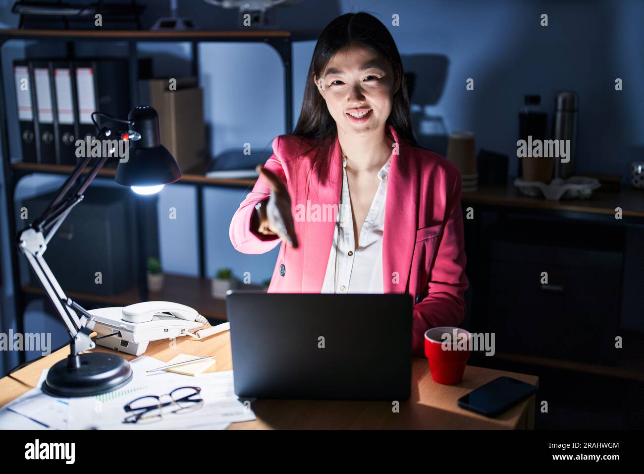 Chinese young woman working at the office at night smiling friendly ...