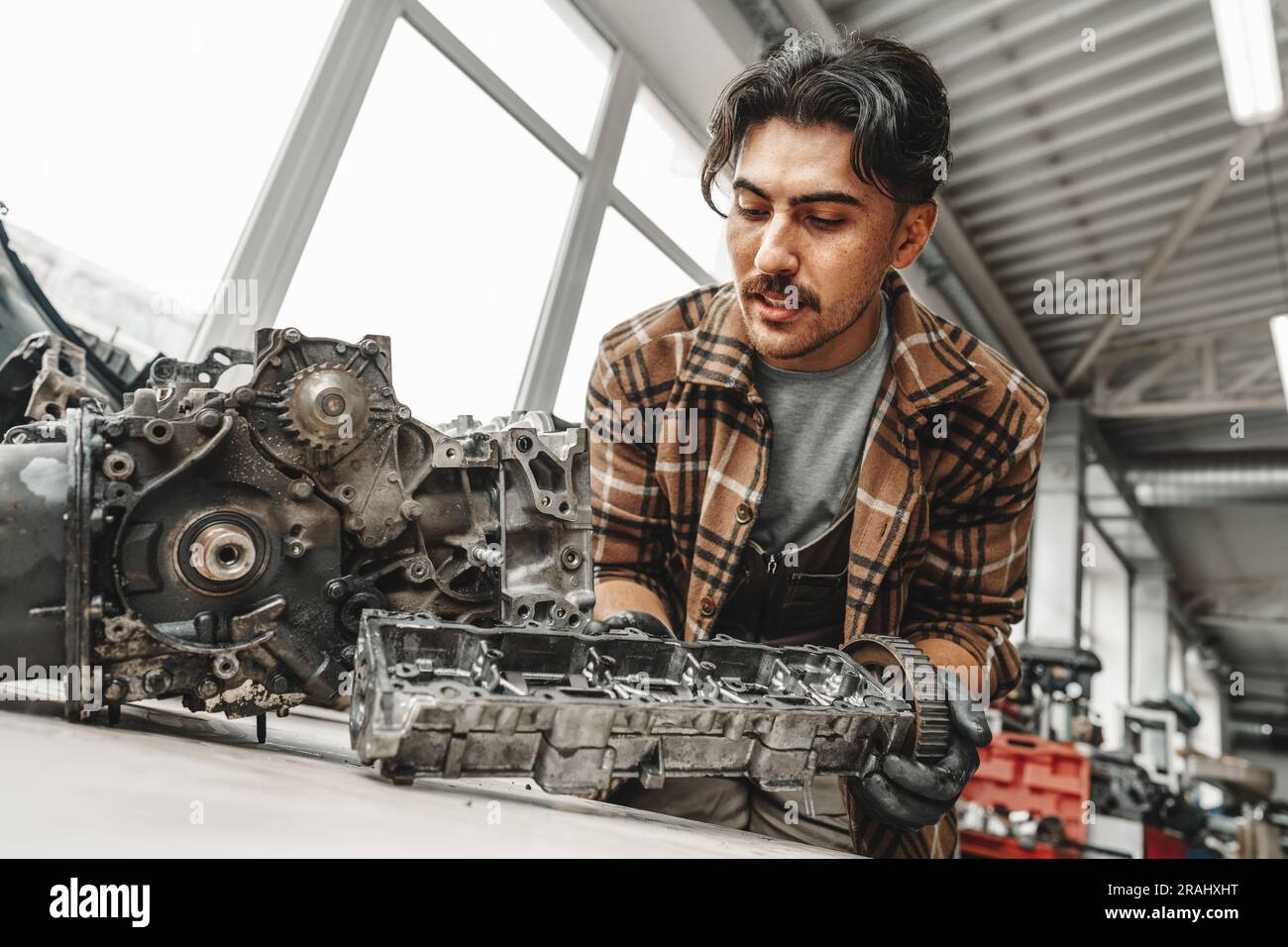 Workman disassembling car engine at the working table of the car ...