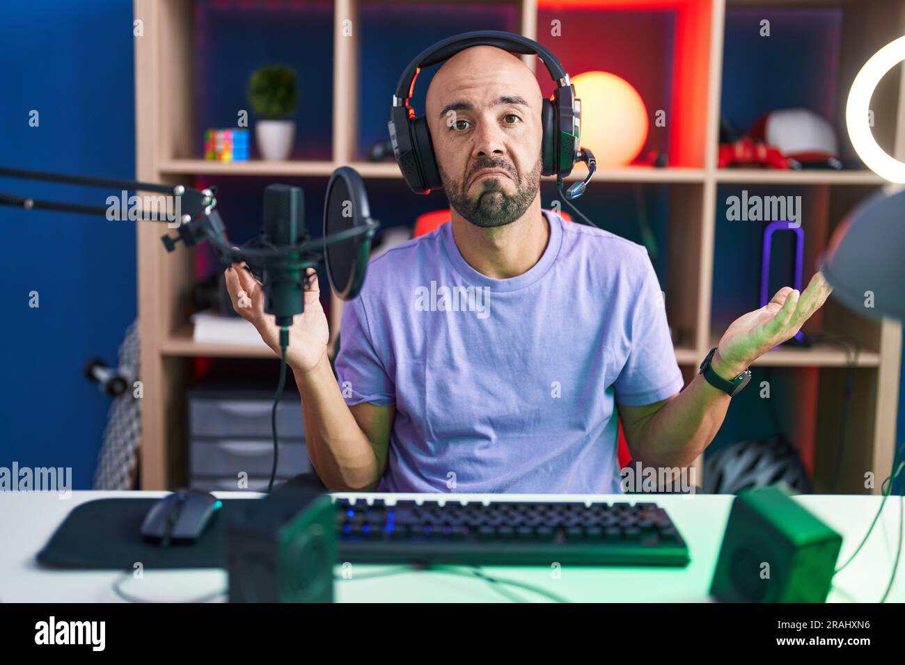 Middle age bald man playing video games wearing headphones shouting and ...