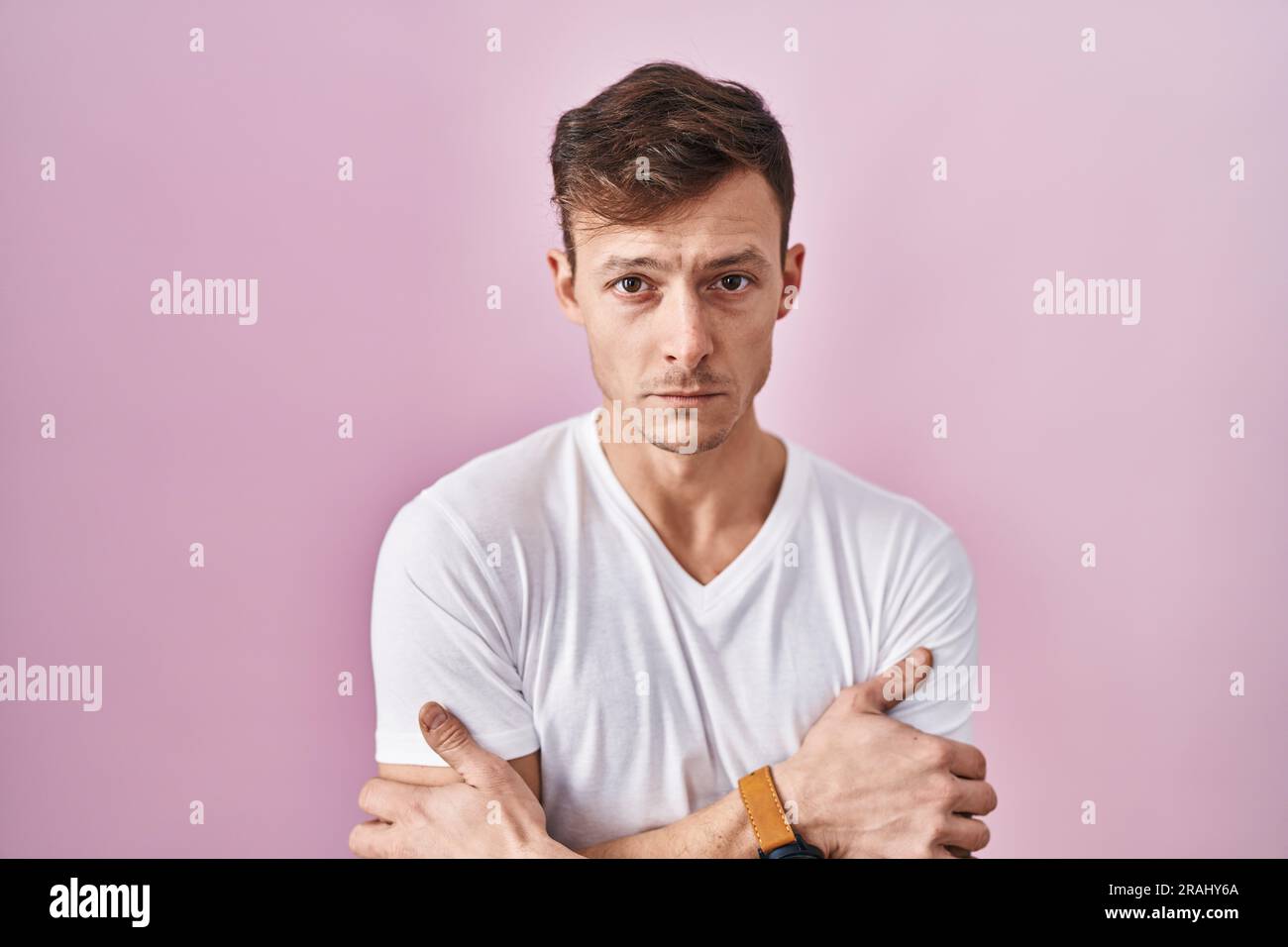 Caucasian man standing over pink background shaking and freezing for ...