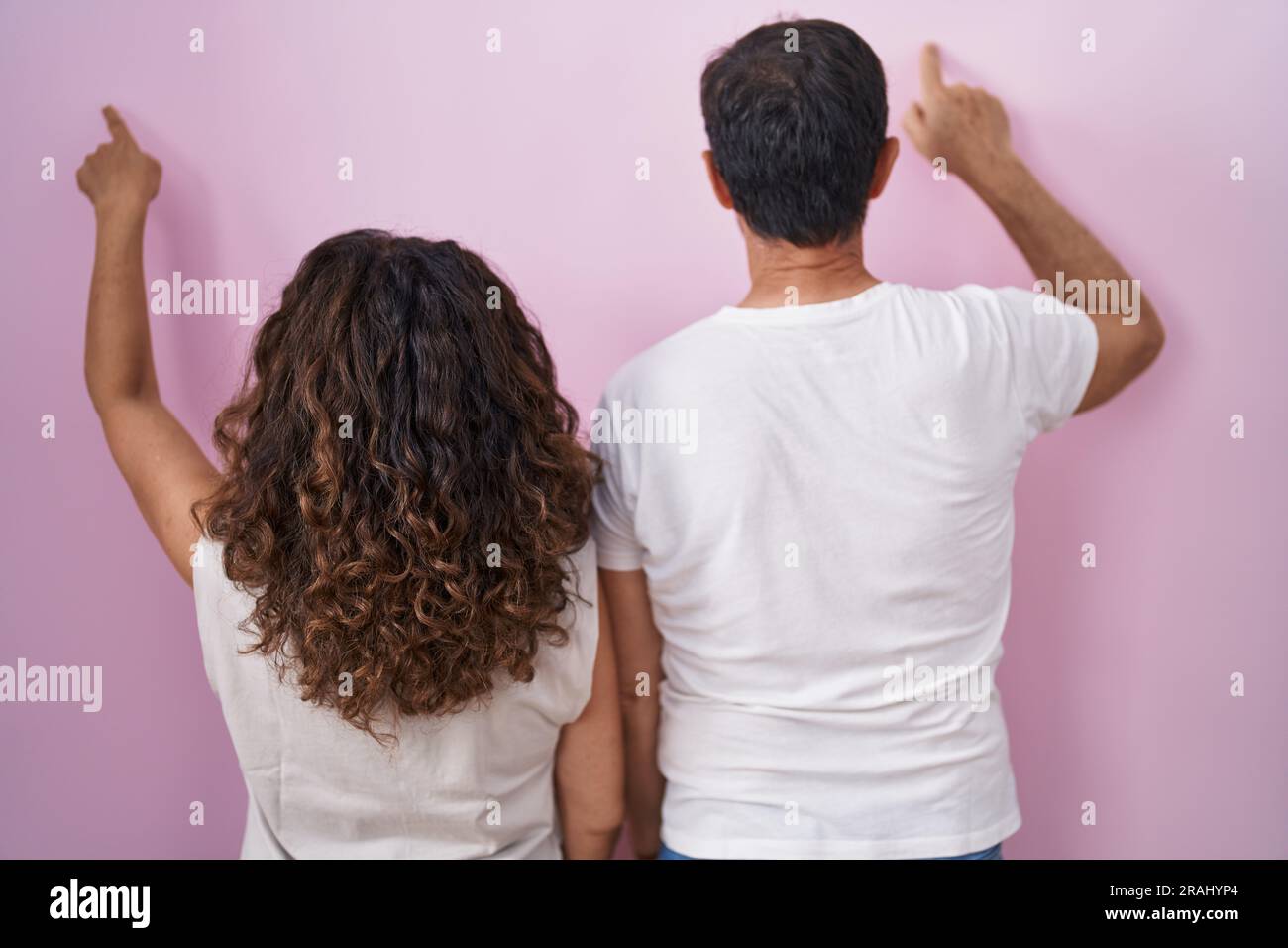 Middle age hispanic couple together over pink background posing ...