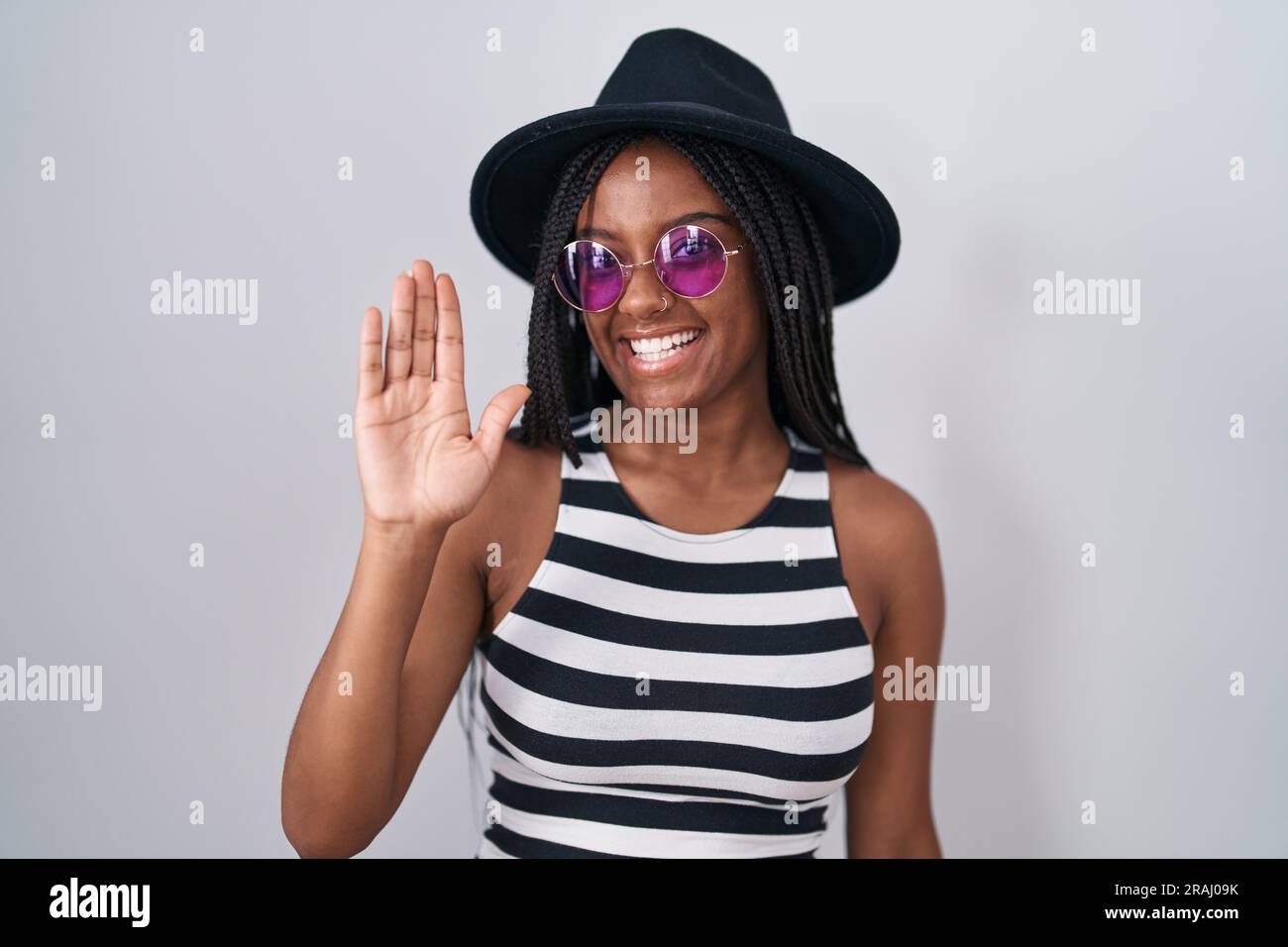 Young african american with braids wearing hat and sunglasses waiving ...