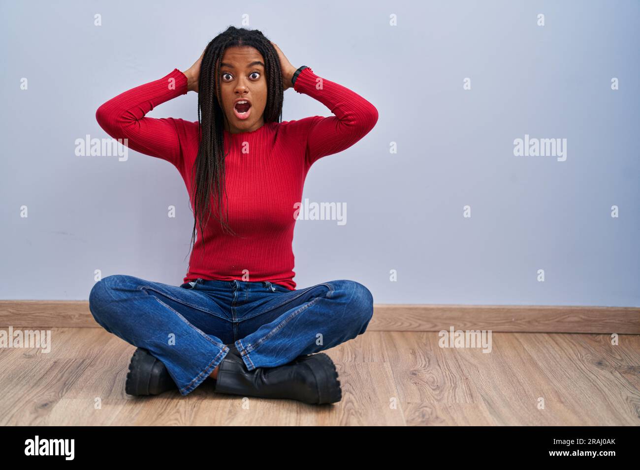 Young african american with braids sitting on the floor at home crazy ...