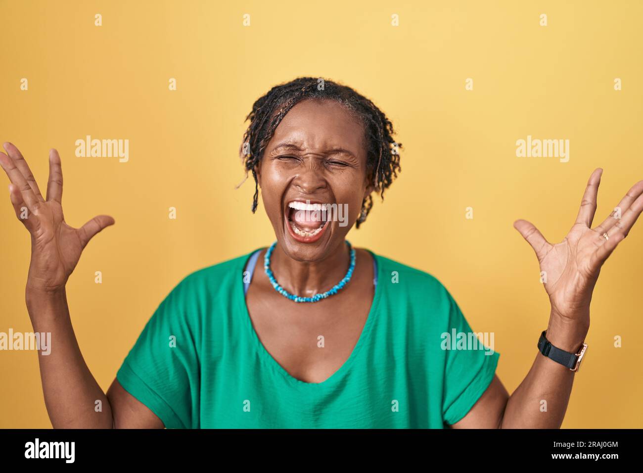African woman with dreadlocks standing over yellow background ...