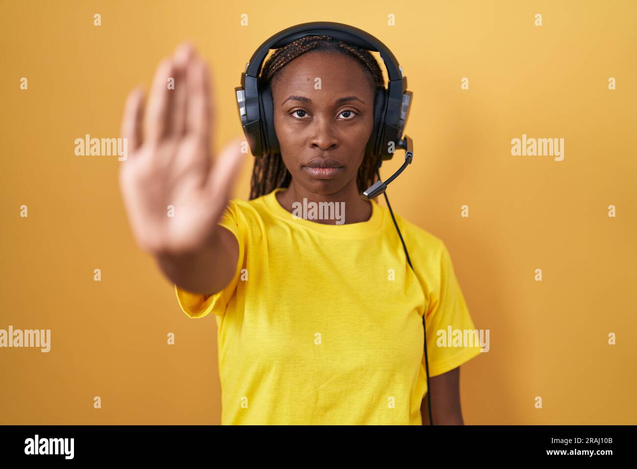 African american woman listening to music using headphones doing stop ...