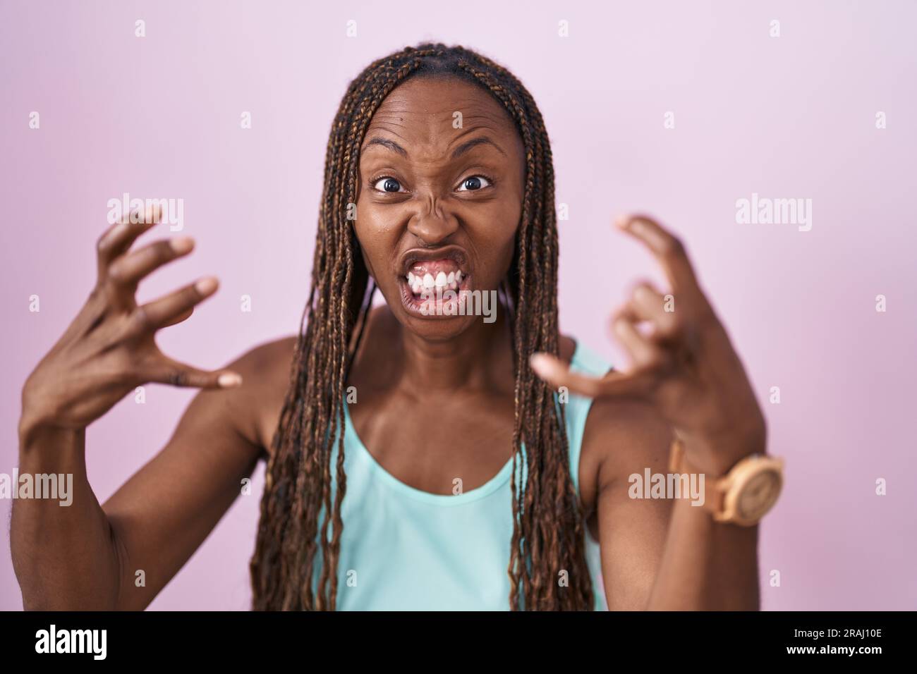 African american woman standing over pink background shouting ...