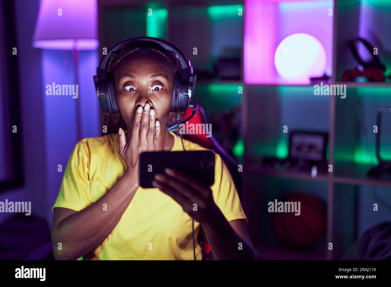 African american woman playing video games with smartphone covering ...