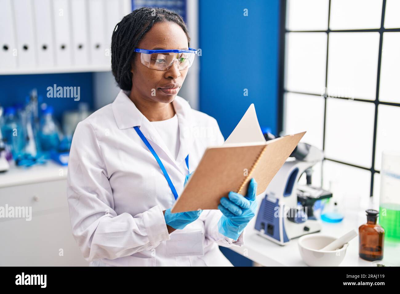 African american woman wearing scientist uniform reading book ...
