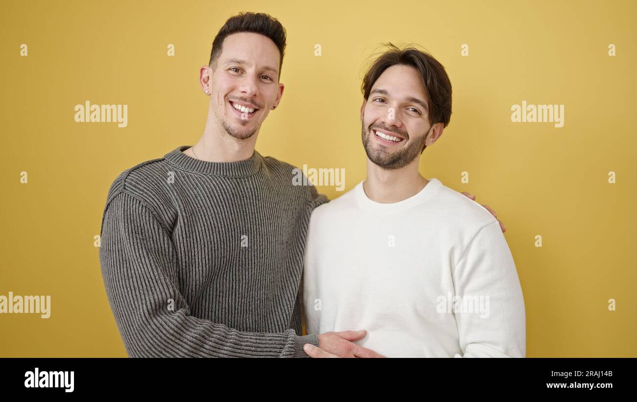 Two men couple hugging each other standing over isolated yellow ...