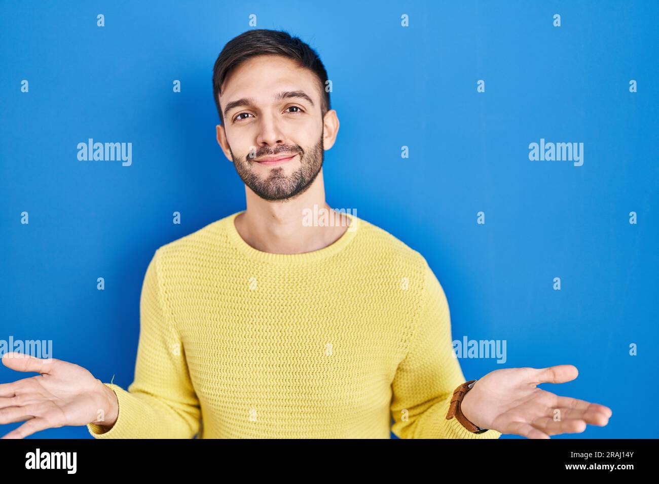 Hispanic man standing over blue background clueless and confused with ...