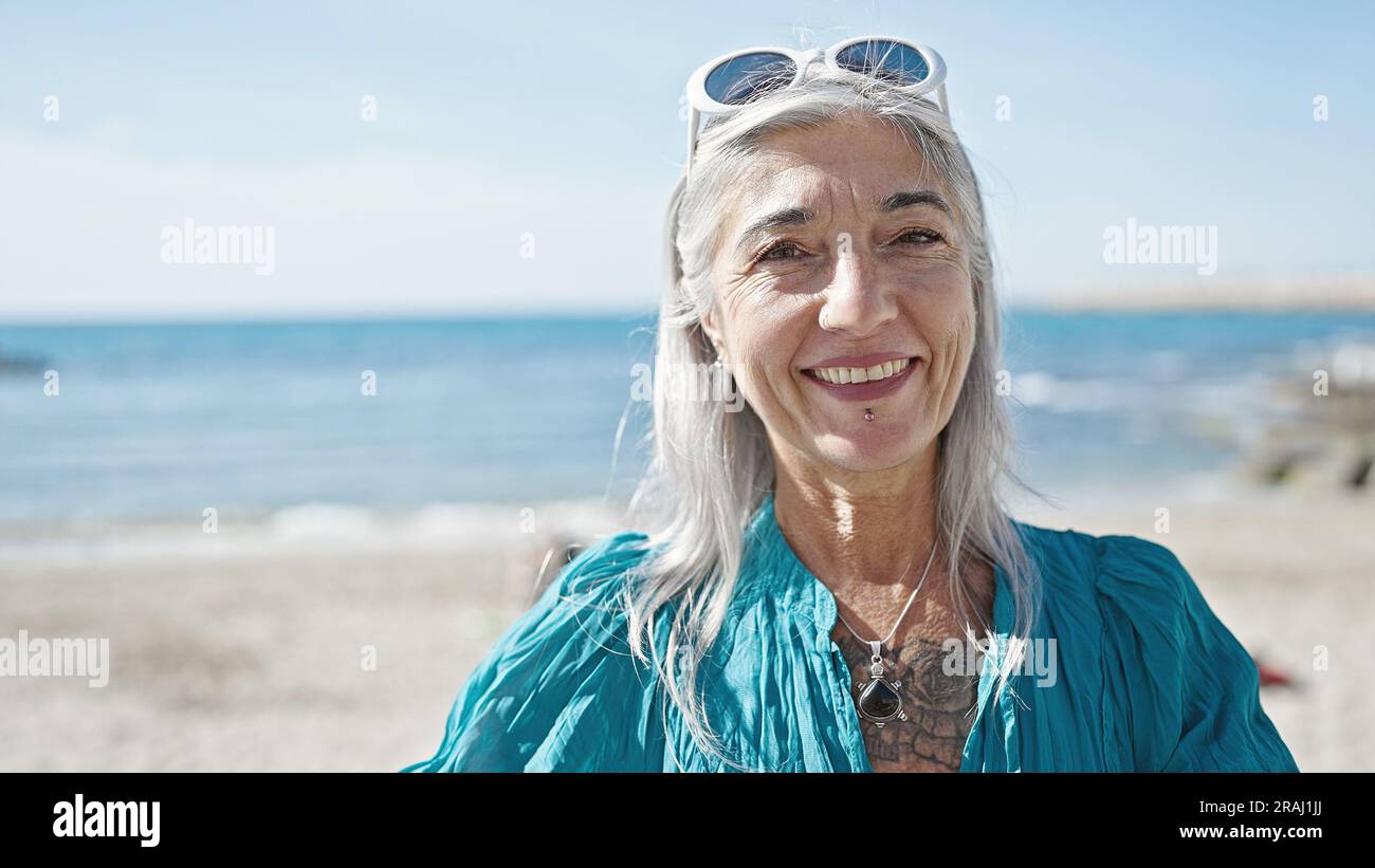 Middle age grey-haired woman smiling confident standing at beach Stock ...