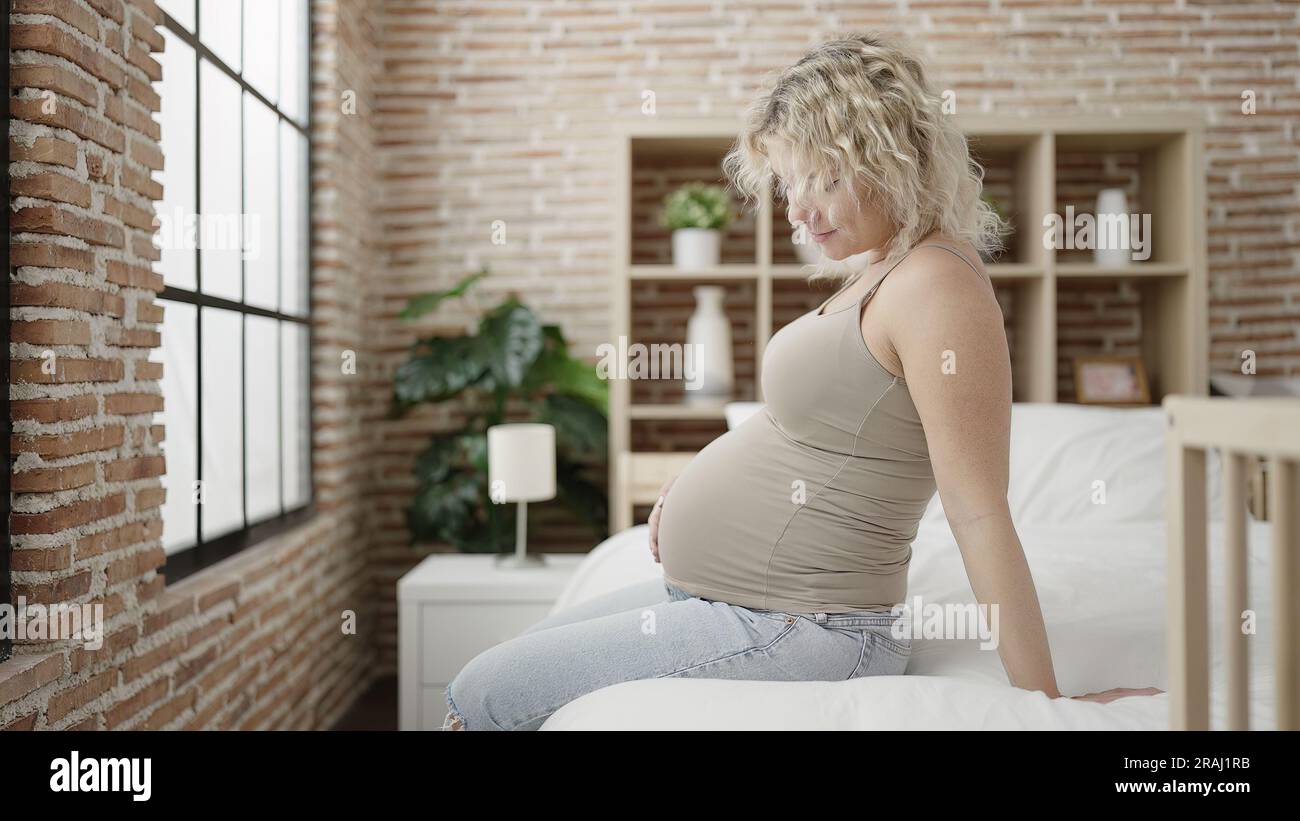 Young Pregnant Woman Touching Belly Sitting On Bed At Bedroom Stock 4992