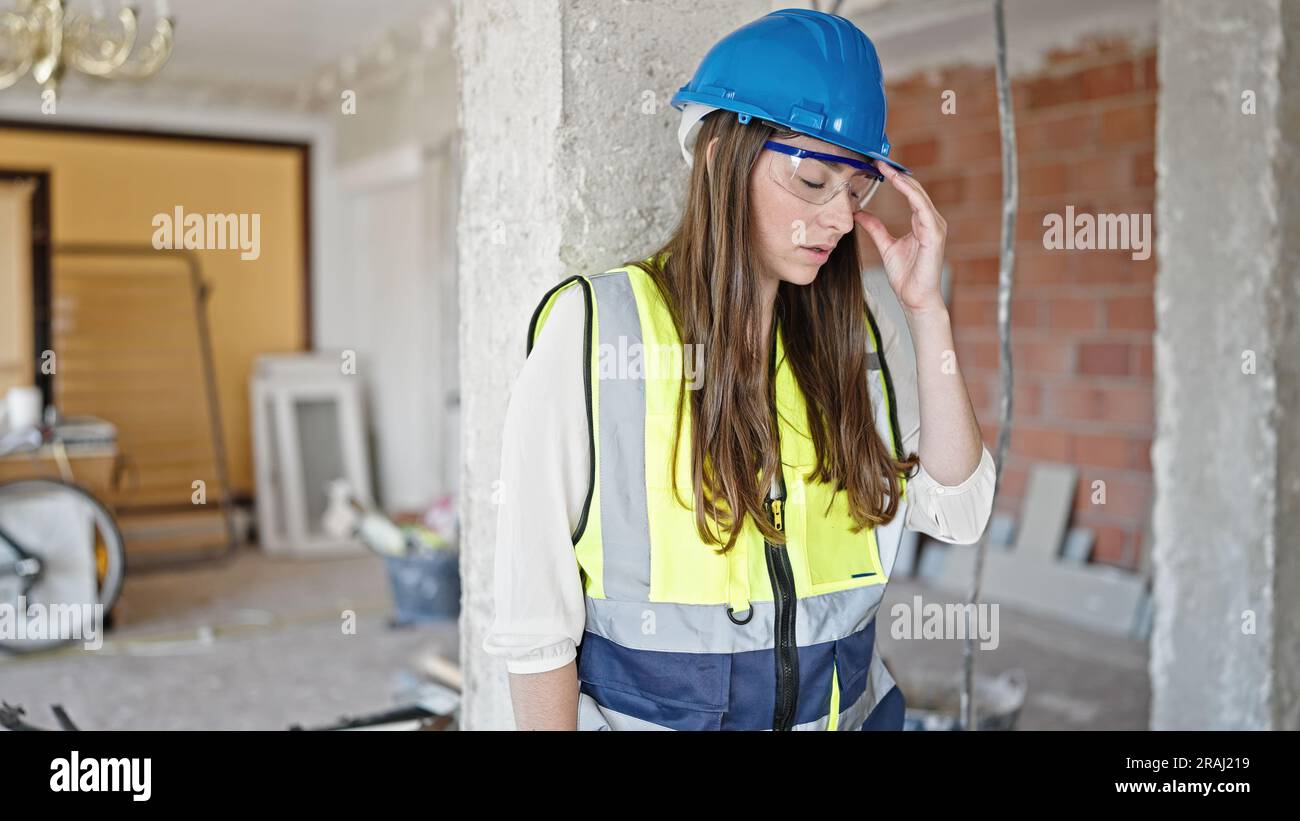 Young beautiful hispanic woman builder standing tired at construction ...