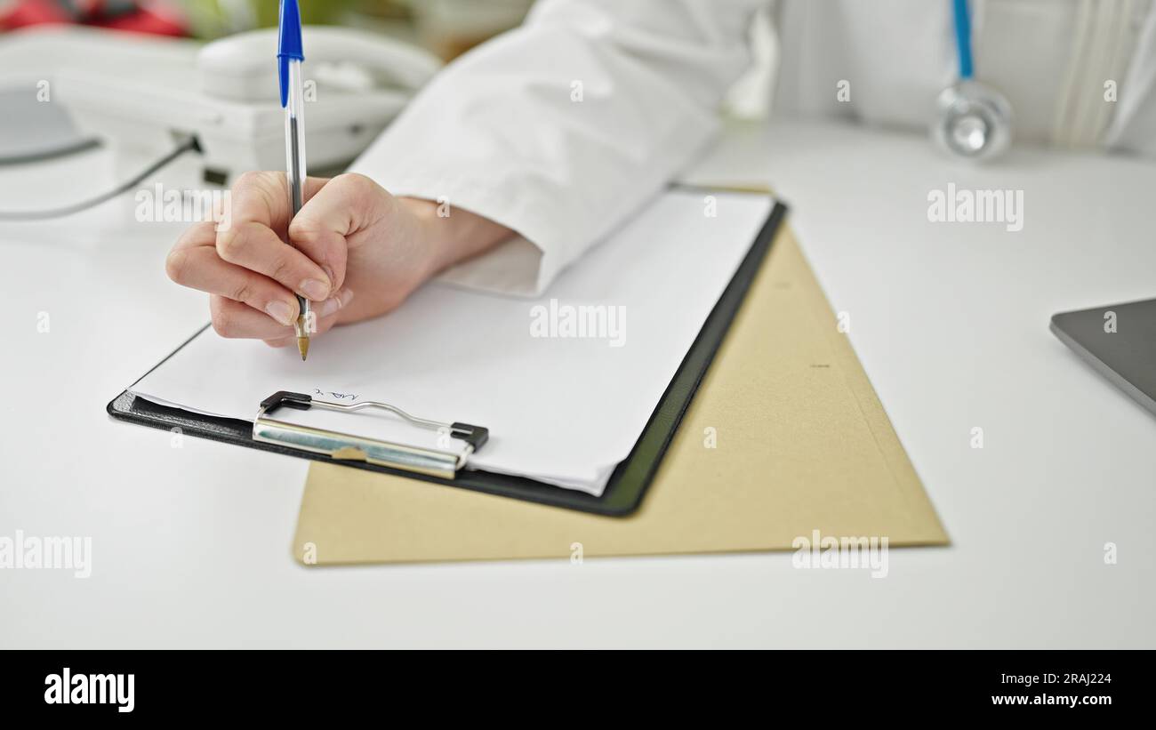 Young beautiful hispanic woman doctor writing medical report at clinic ...