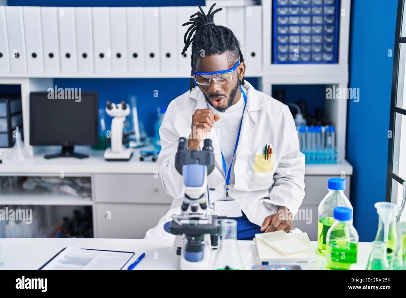 African man with dreadlocks working at scientist laboratory feeling ...