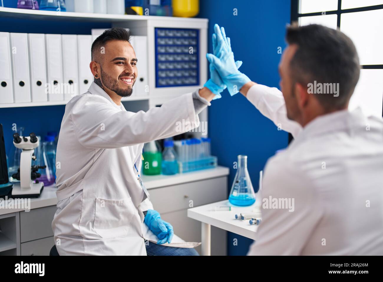 Two men scientists smiling confident high five with hands raised up at ...