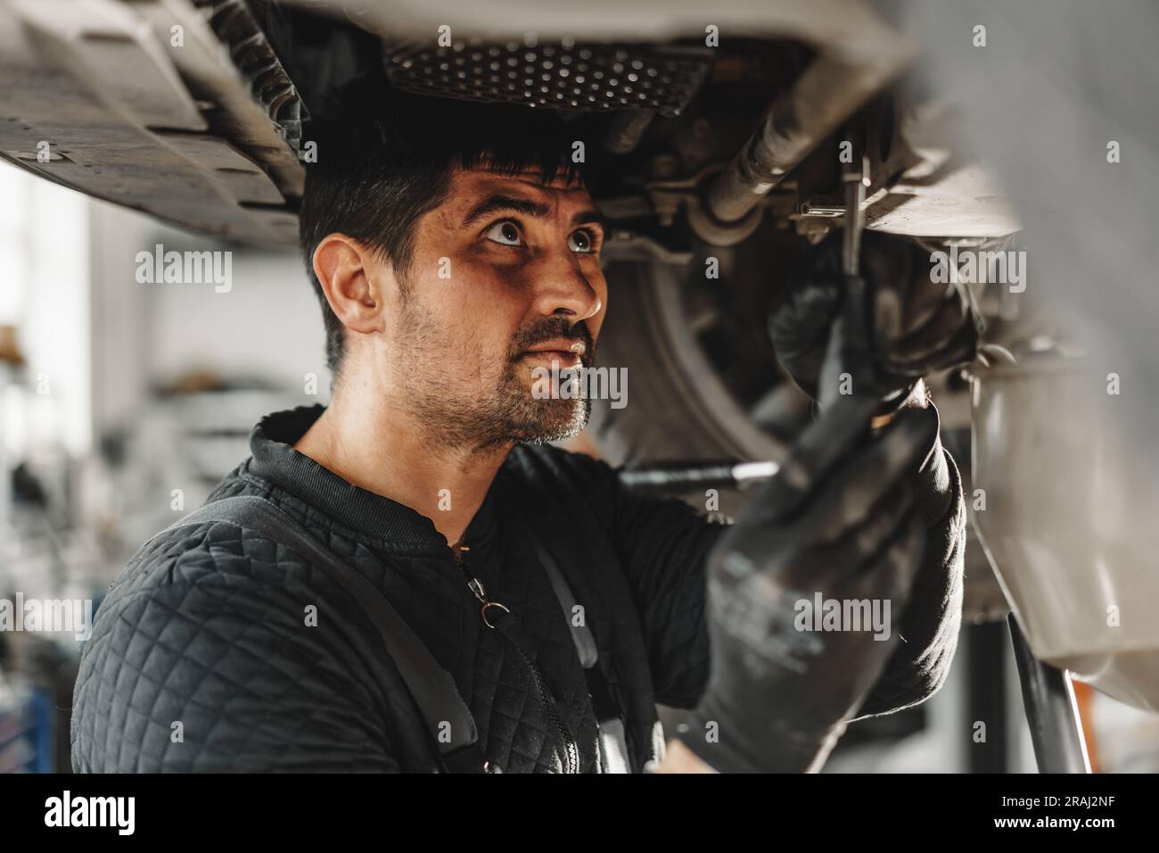 Workman mechanic working under car in auto repair shop Stock Photo - Alamy