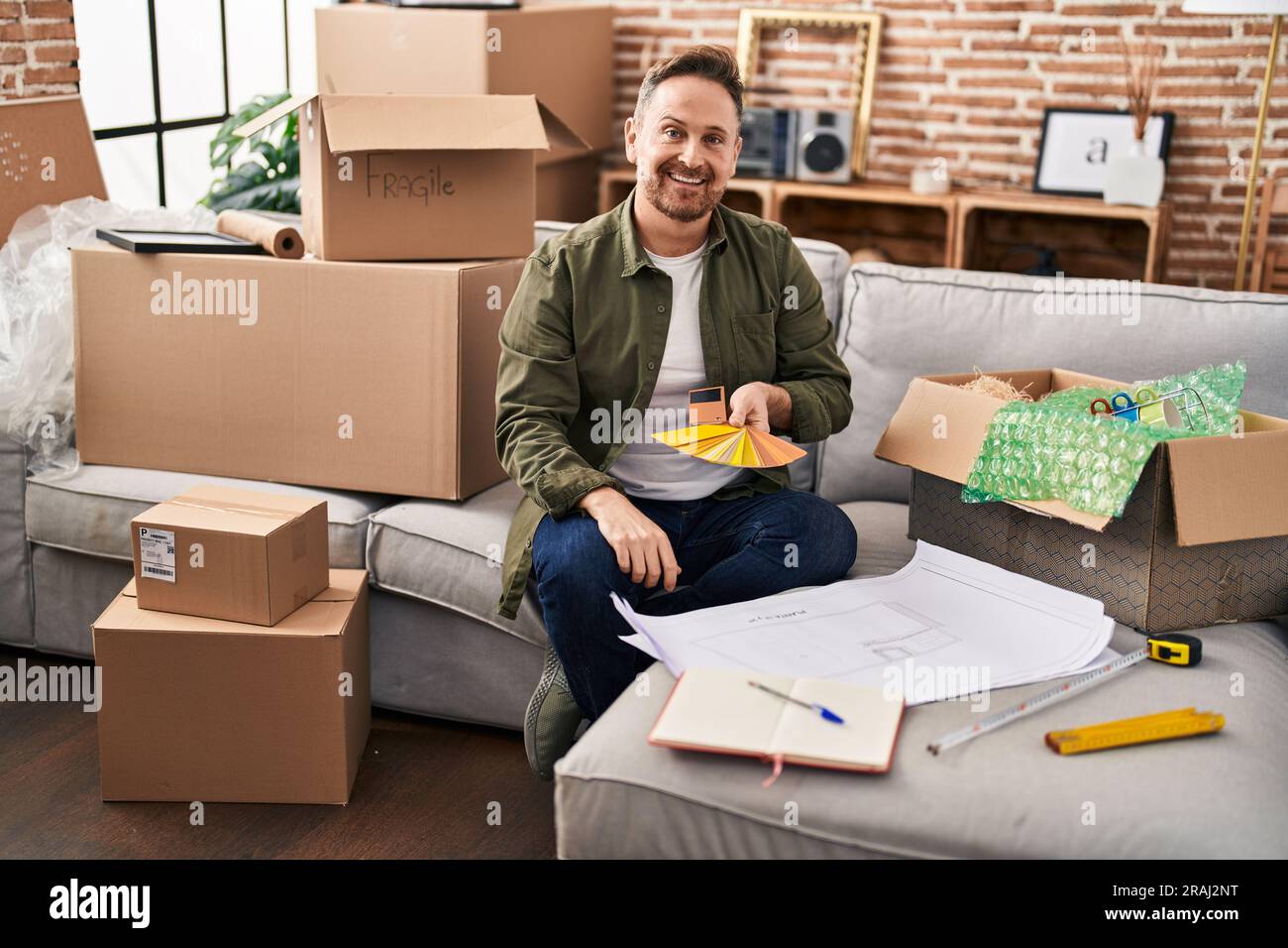 Young caucasian man holding test color looking house plans at new home ...